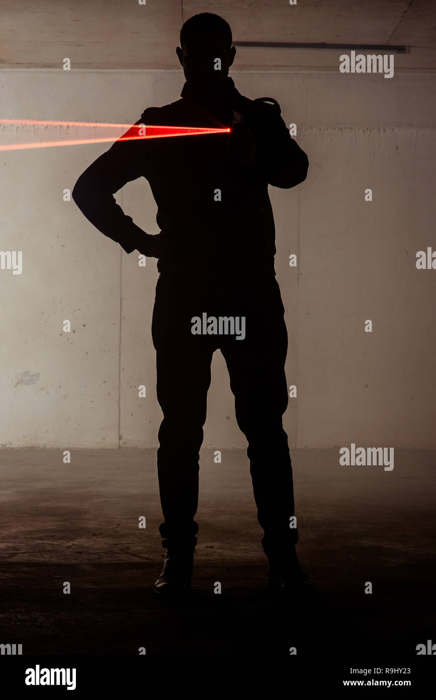 Silhouette of a man standing still with a gun in his hands Stock Photo ...