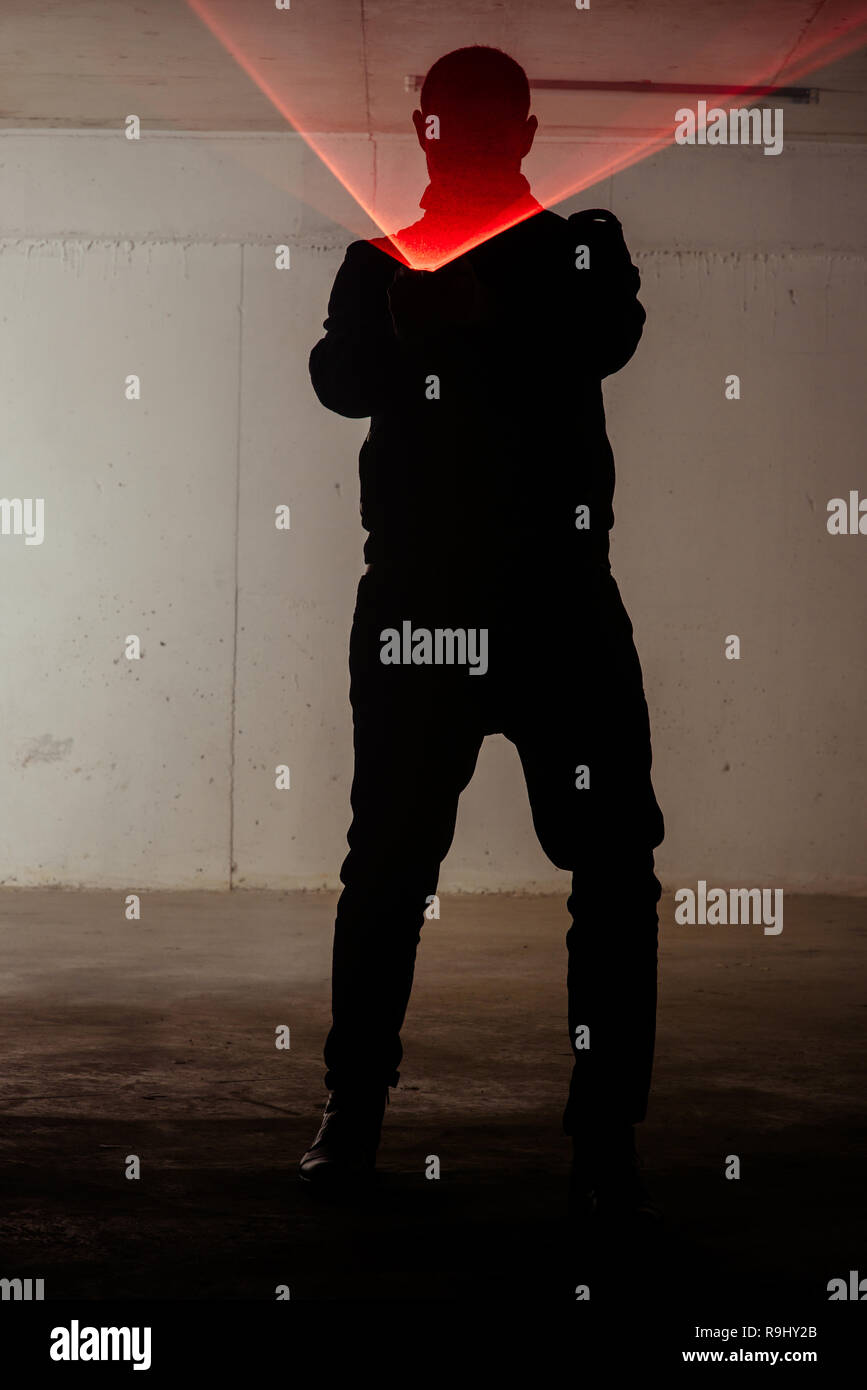 A male assassin person is holding gun with laser in a dark room Stock ...