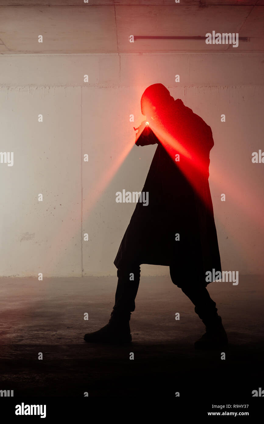 Assassin silhouette of a male person who is standing in dark room and ...