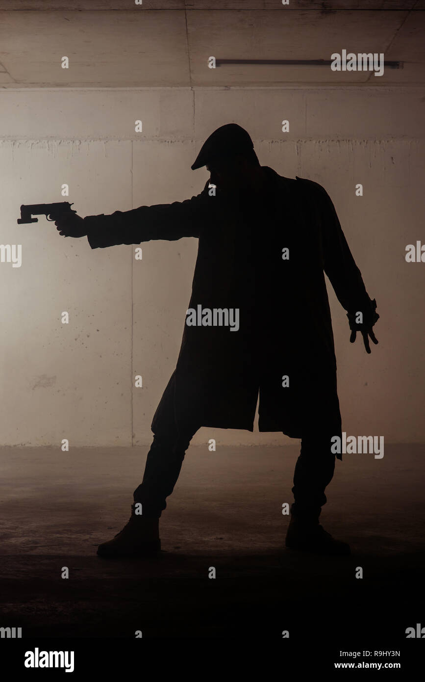 Shape of a assassin man who is holding gun in his hands Stock Photo - Alamy