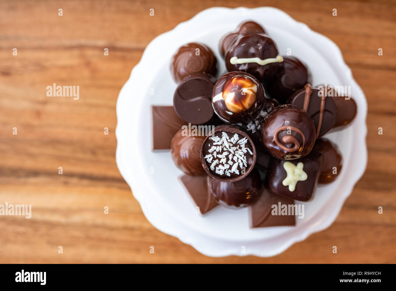 Assorted fancy milk and dark chocolate candy on a white cake plate on a ...