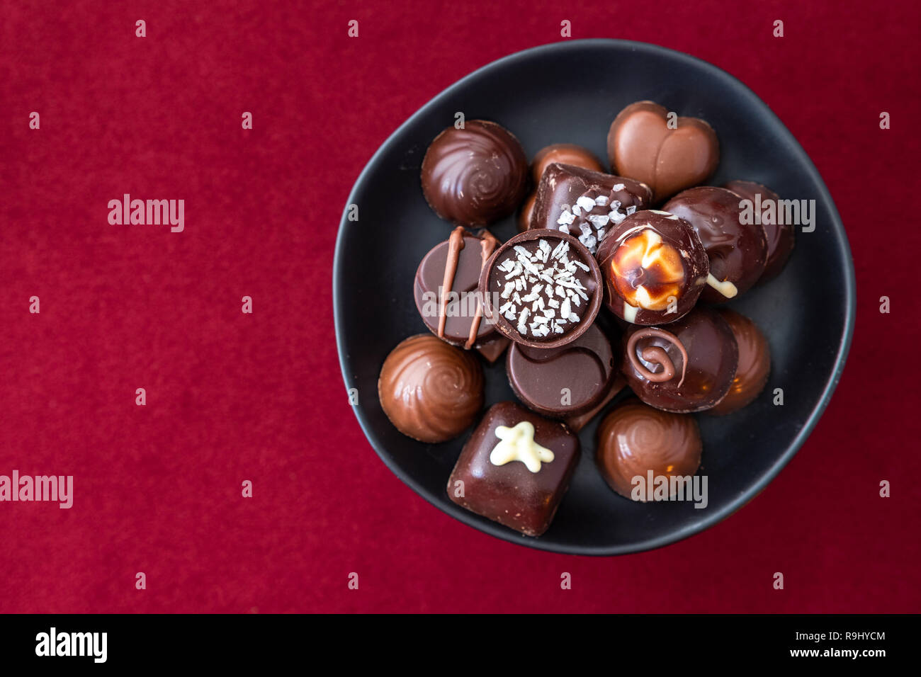 Assorted fancy milk and dark chocolate candy on a rustic black plate on ...