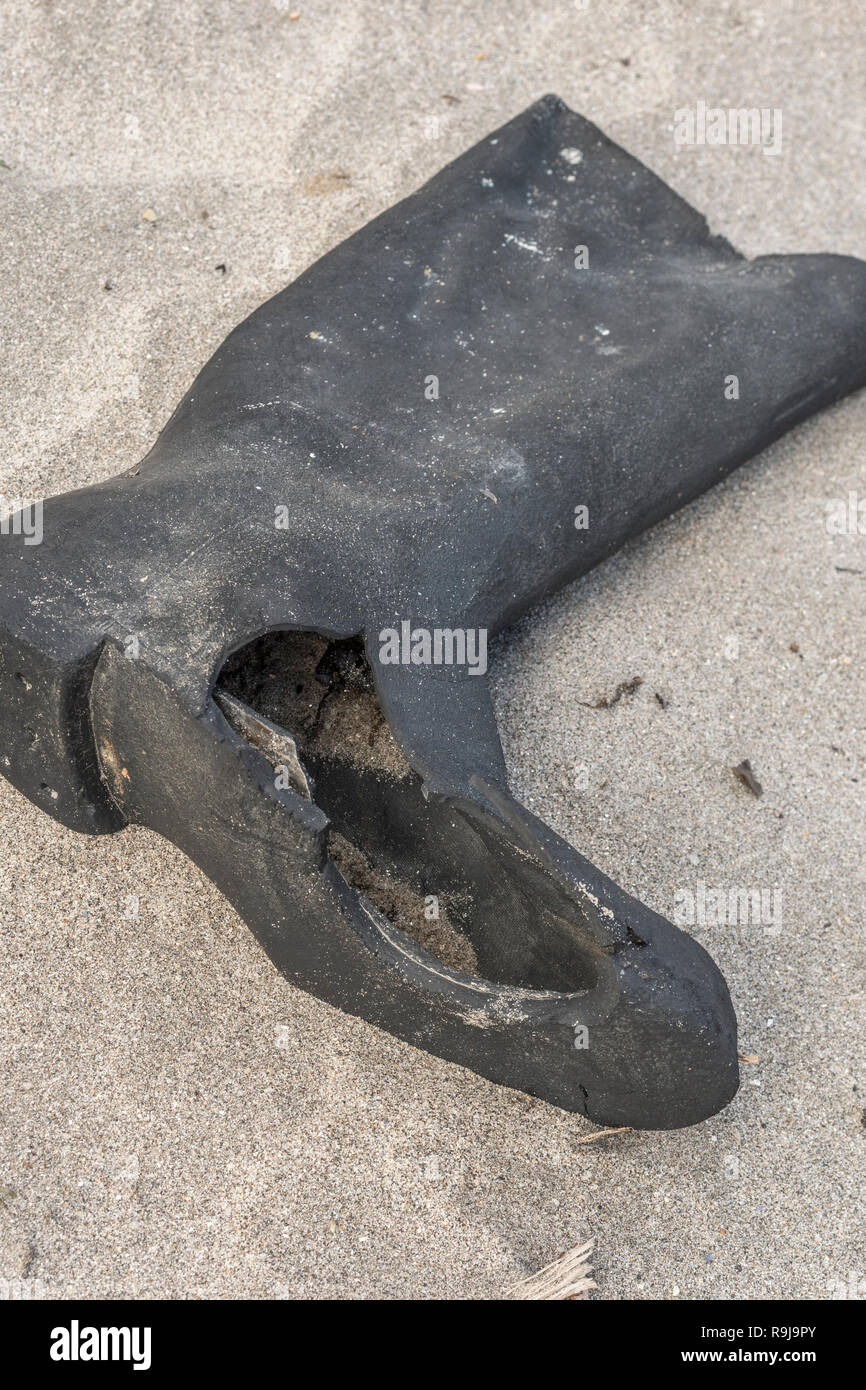 Old rubber boot washed up on shore & polluting shoreline. For plastic ...