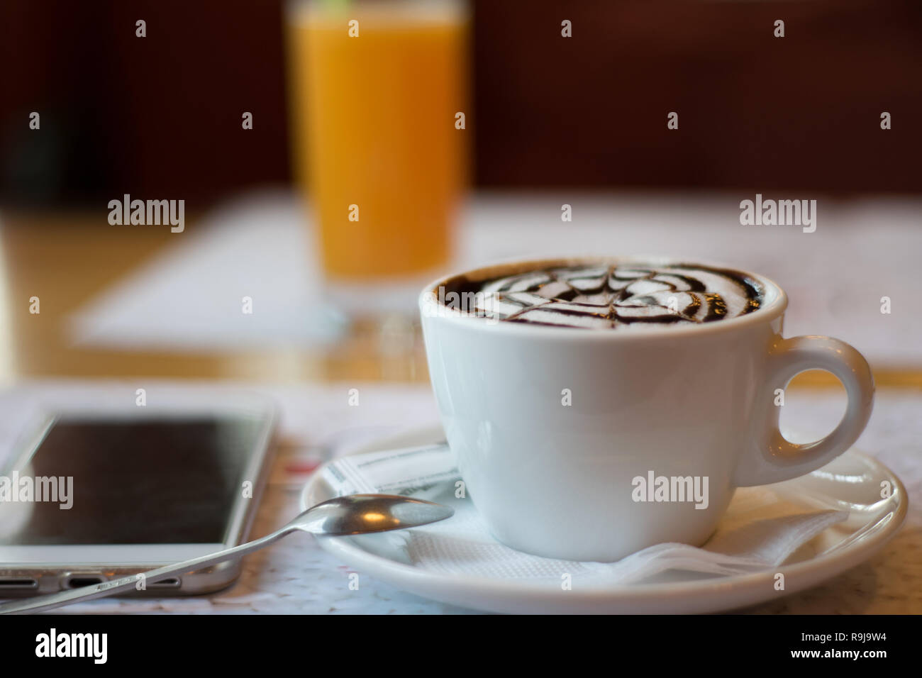 still life with a cup of flavored cappuccino, a phone on the background ...