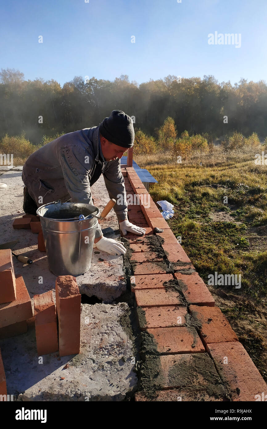 the artist masonry a wall of red bricks in the open air in the village ...