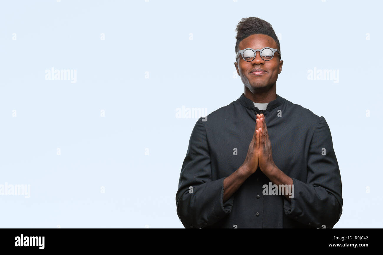 Young african american priest man over isolated background praying with ...