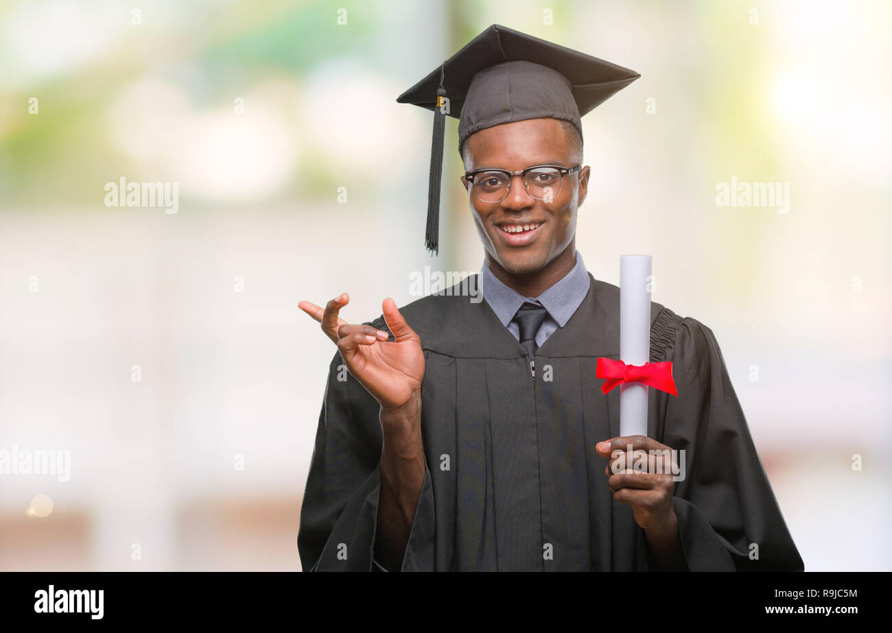 Young graduated african american man holding degree over isolated ...