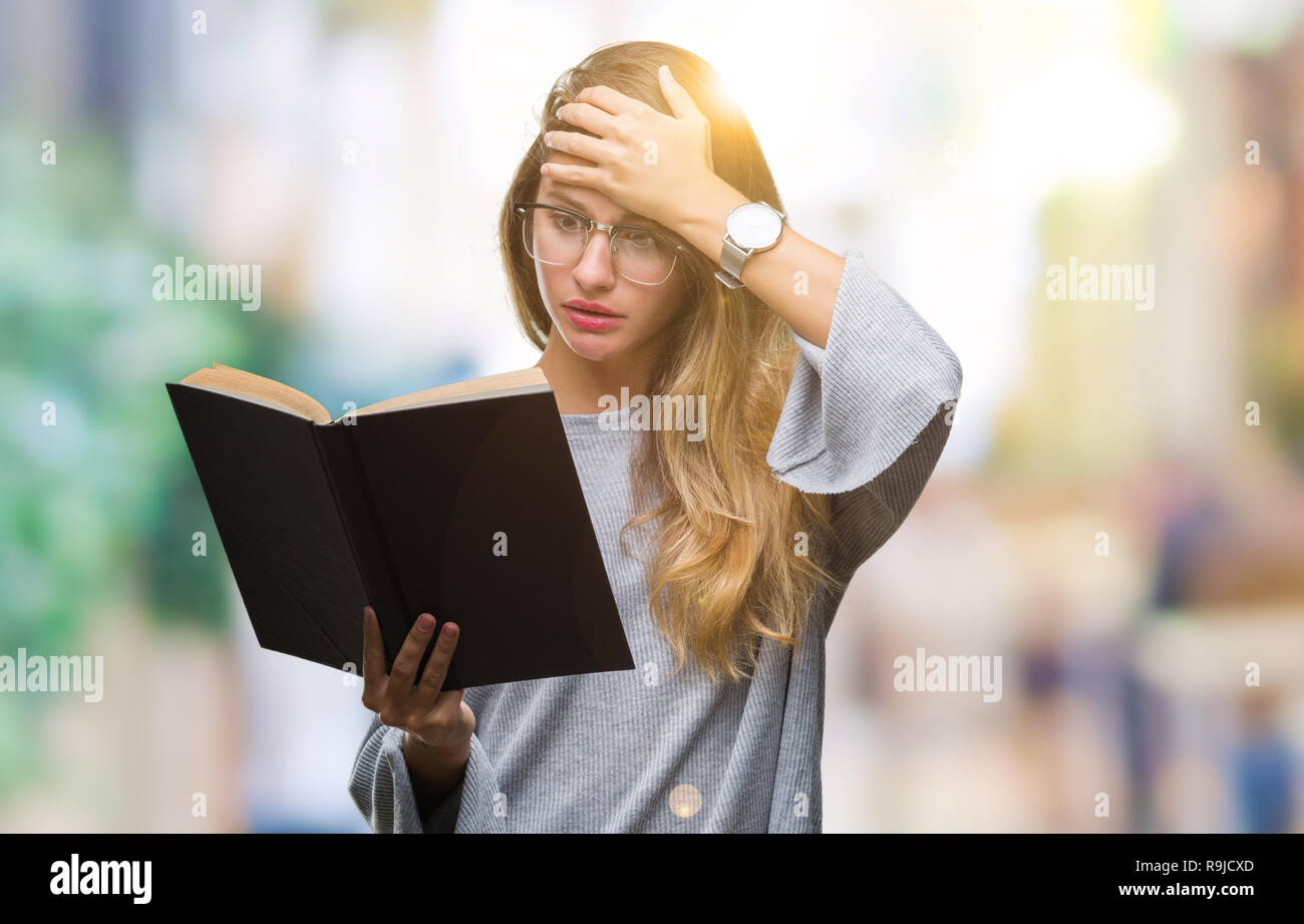 Young beautiful blonde woman reading a book over isolated background ...