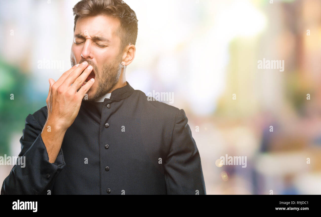 Young catholic christian priest man over isolated background bored ...