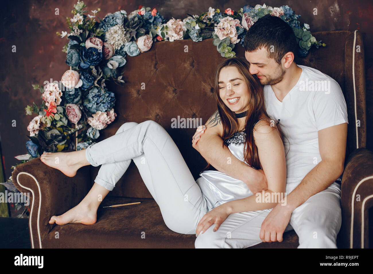 Pretty couple sitting on a brown chair. Family at home Stock Photo - Alamy