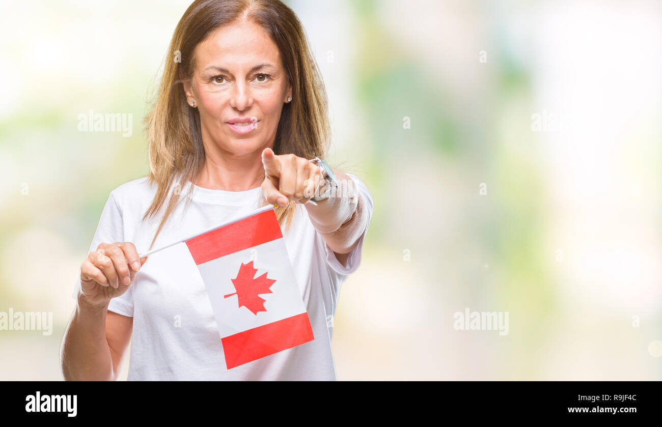 Middle age hispanic woman holding flag of Canada over isolated ...