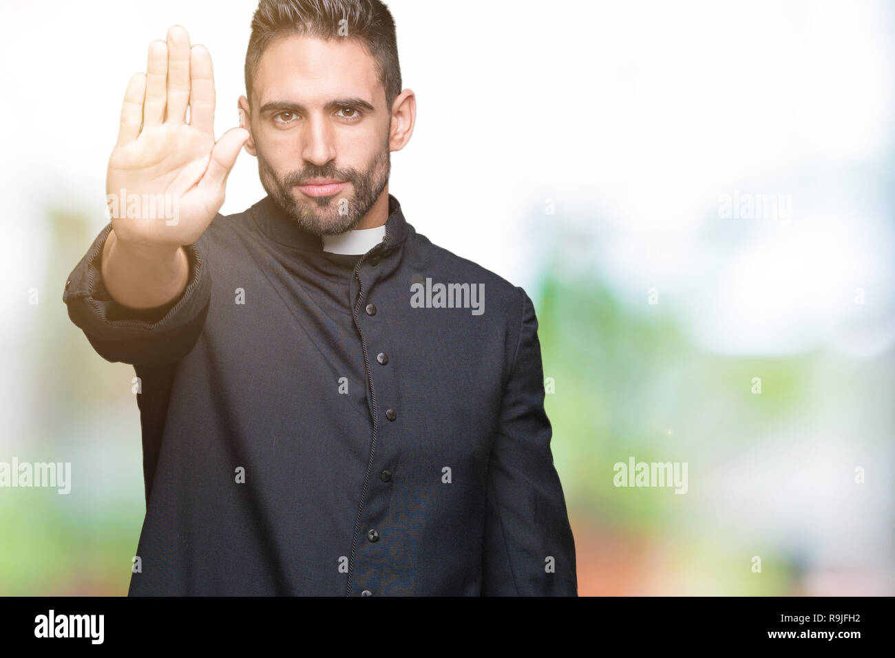 Young Christian priest over isolated background doing stop sing with ...