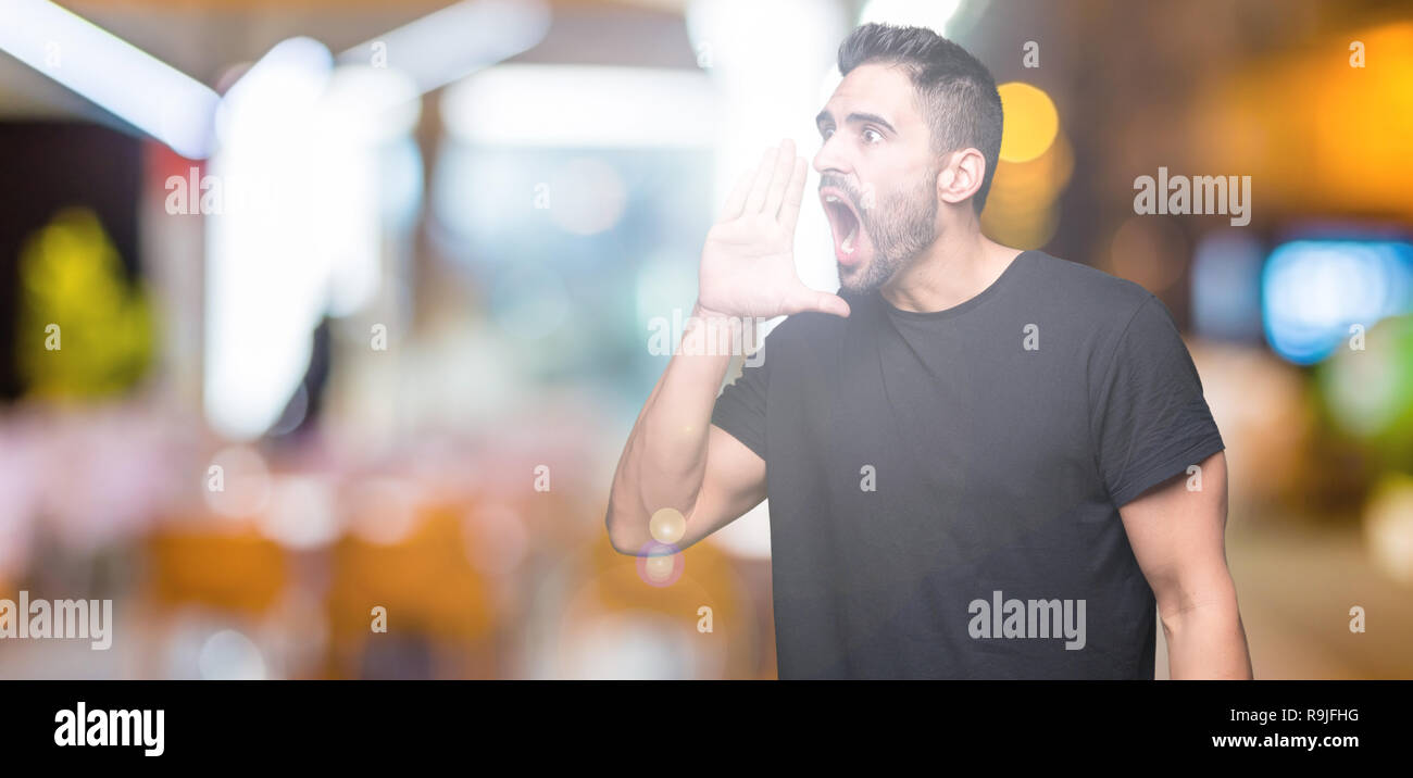 Young handsome man over isolated background shouting and screaming loud ...