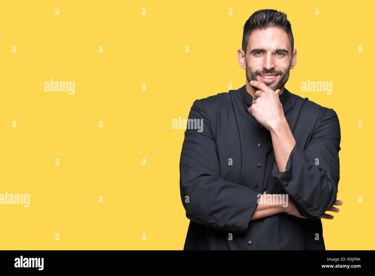 Young Christian priest over isolated background looking confident at ...