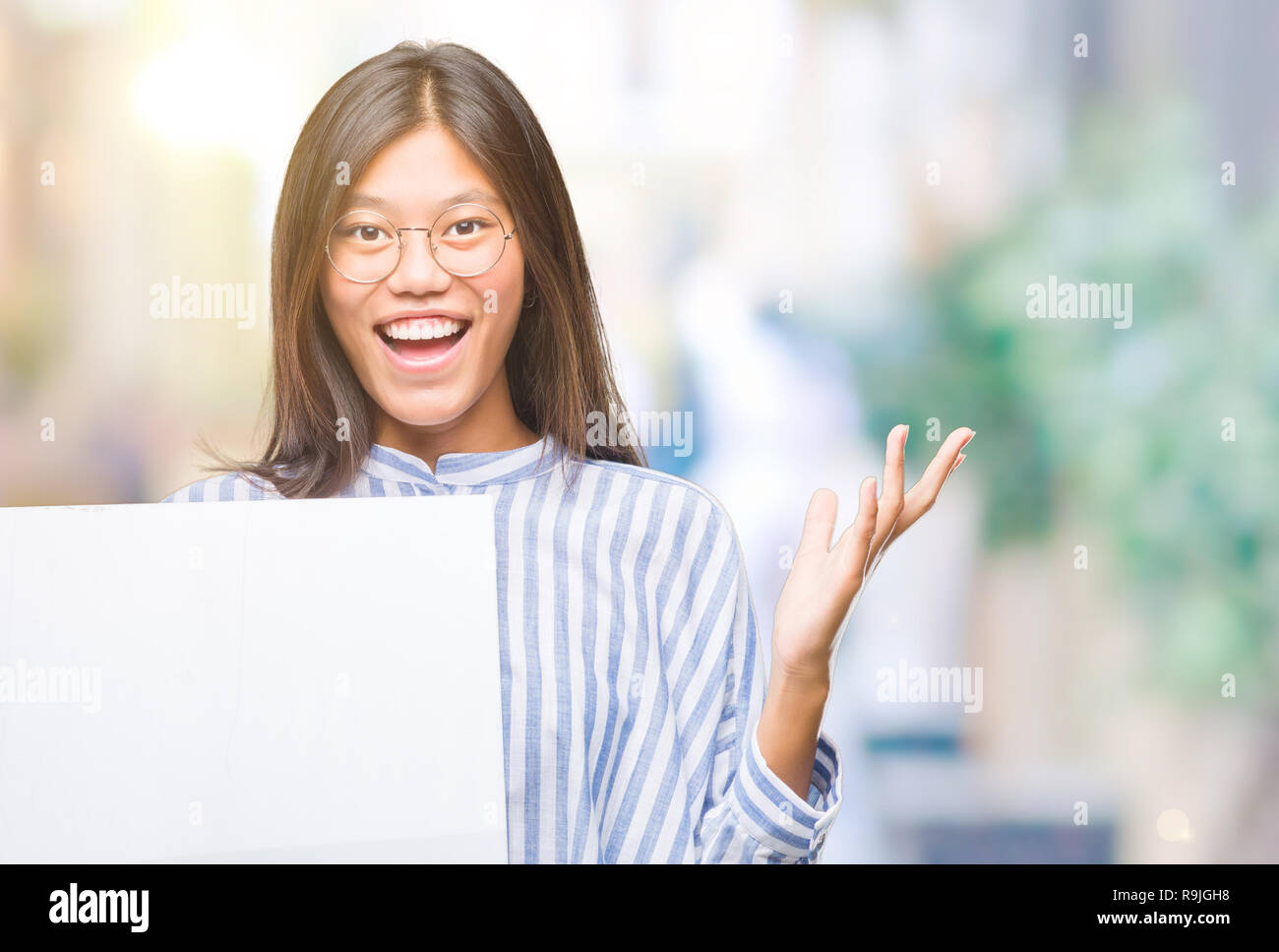 Young asian woman over isolated background holding blank banner very ...