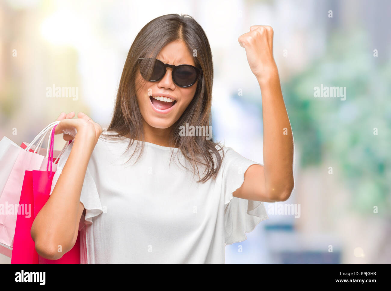 Young asian woman holding shopping bags on sales over isolated ...