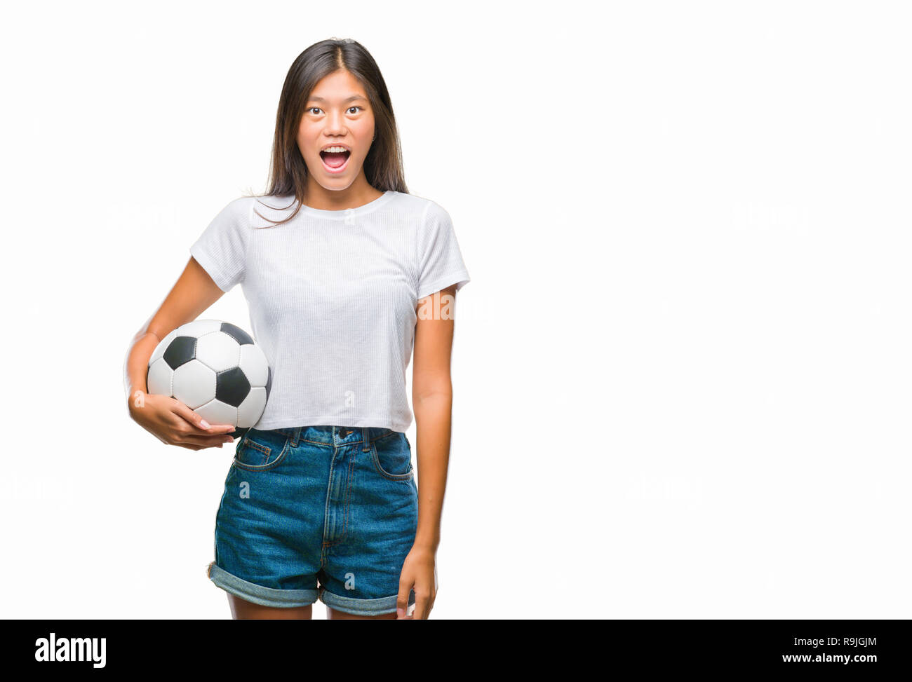 Young asian woman holding football soccer ball over isolated background ...
