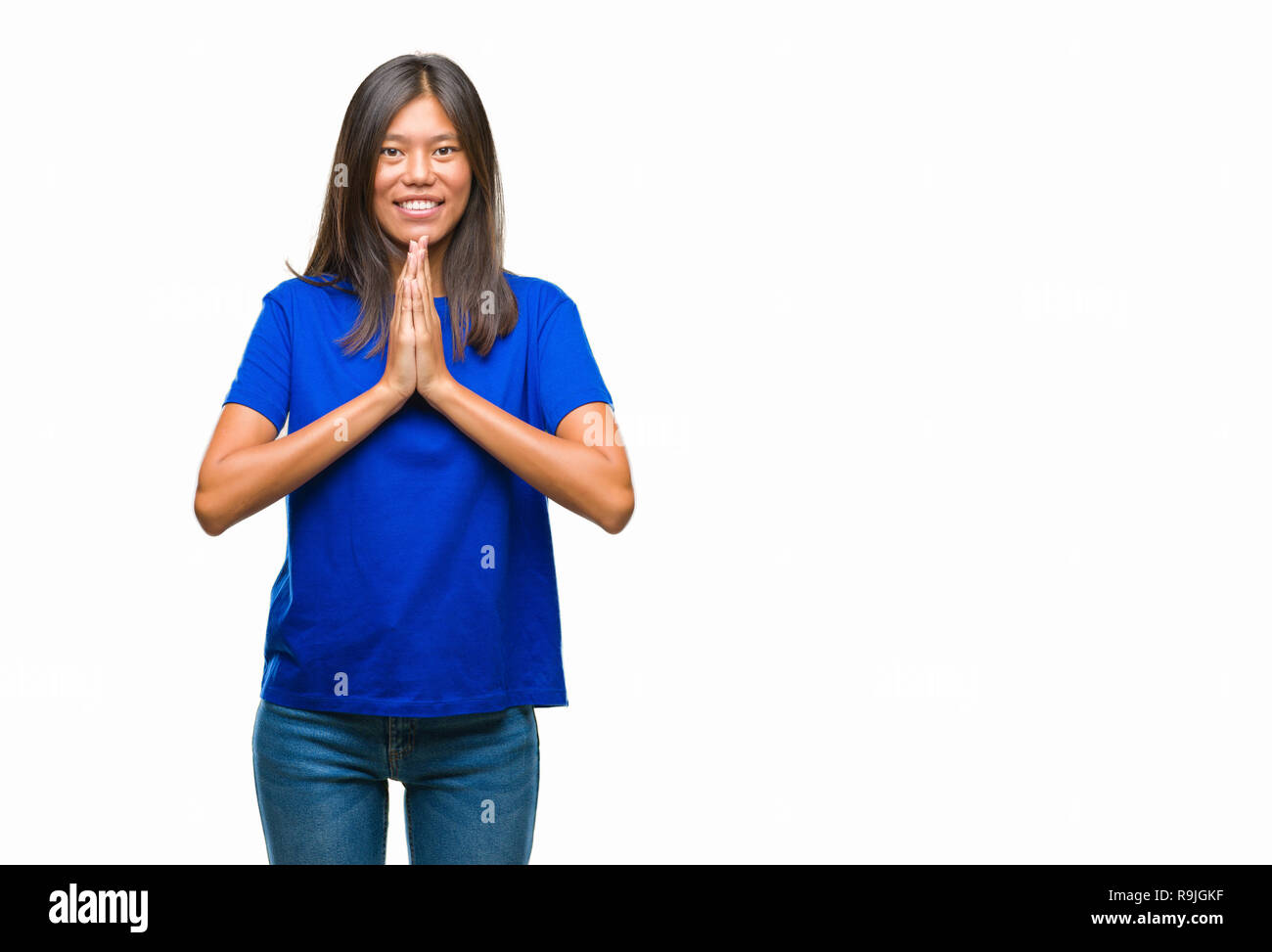 Young asian woman over isolated background praying with hands together ...