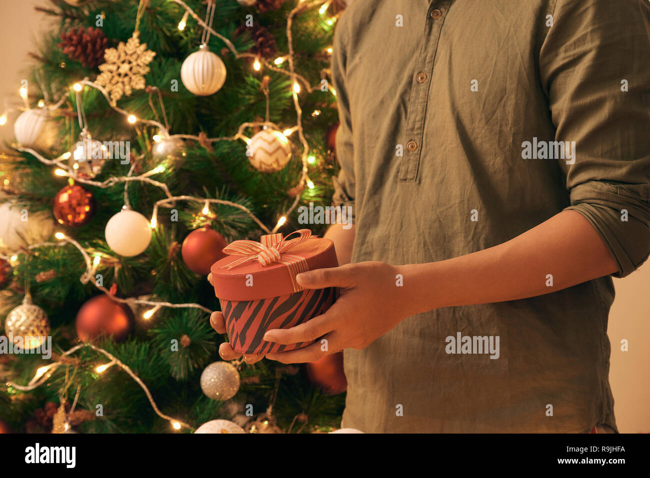 Close-up young asian man holding a christmas red gift box on sofa and ...