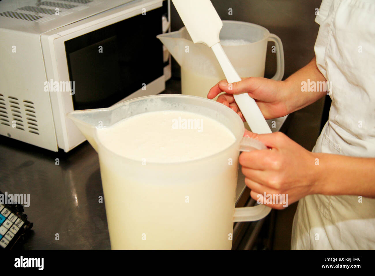 Ice cream ingredients mix together with blender. Female chef is mixing ...
