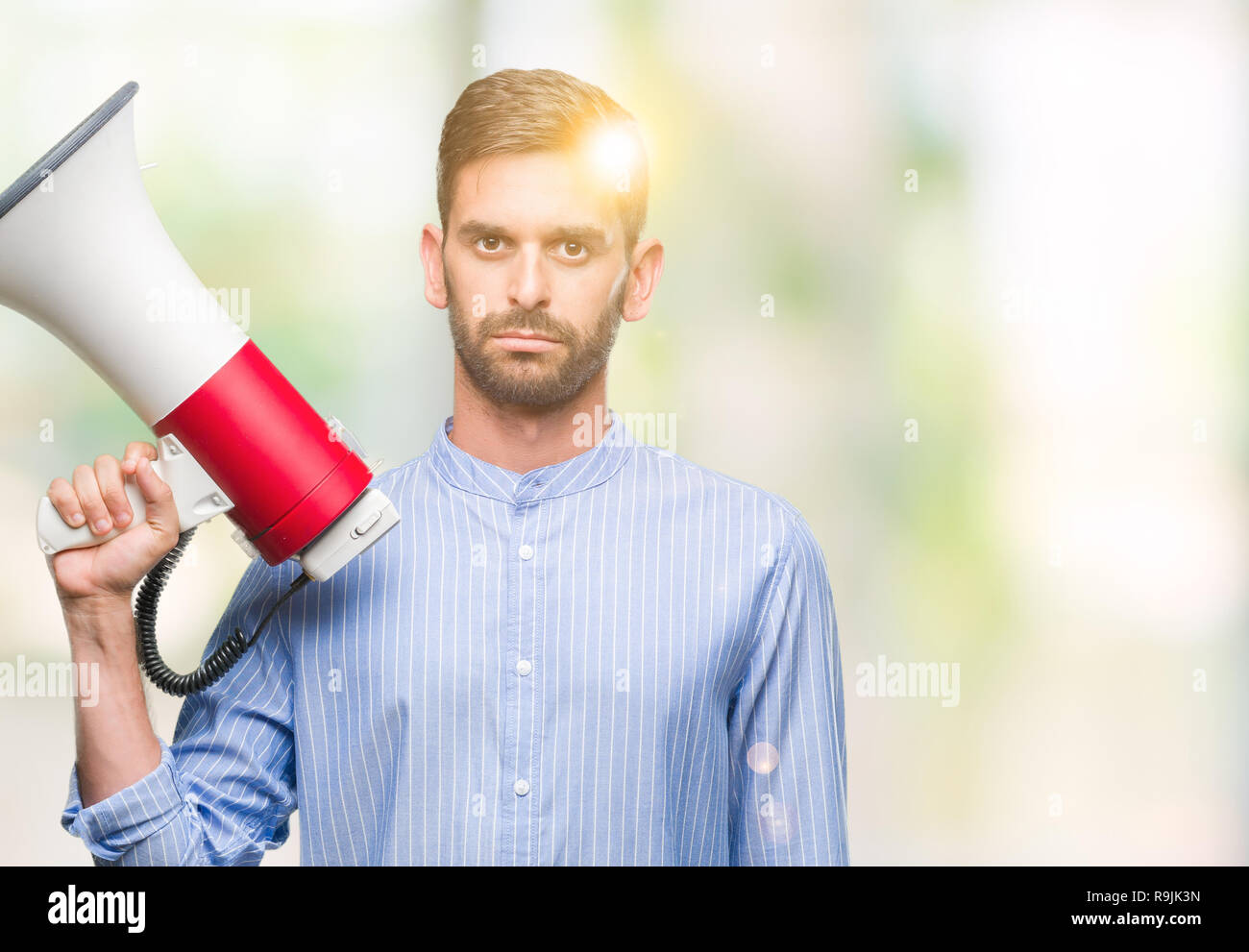 Young handsome man yelling through megaphone over isolated background ...