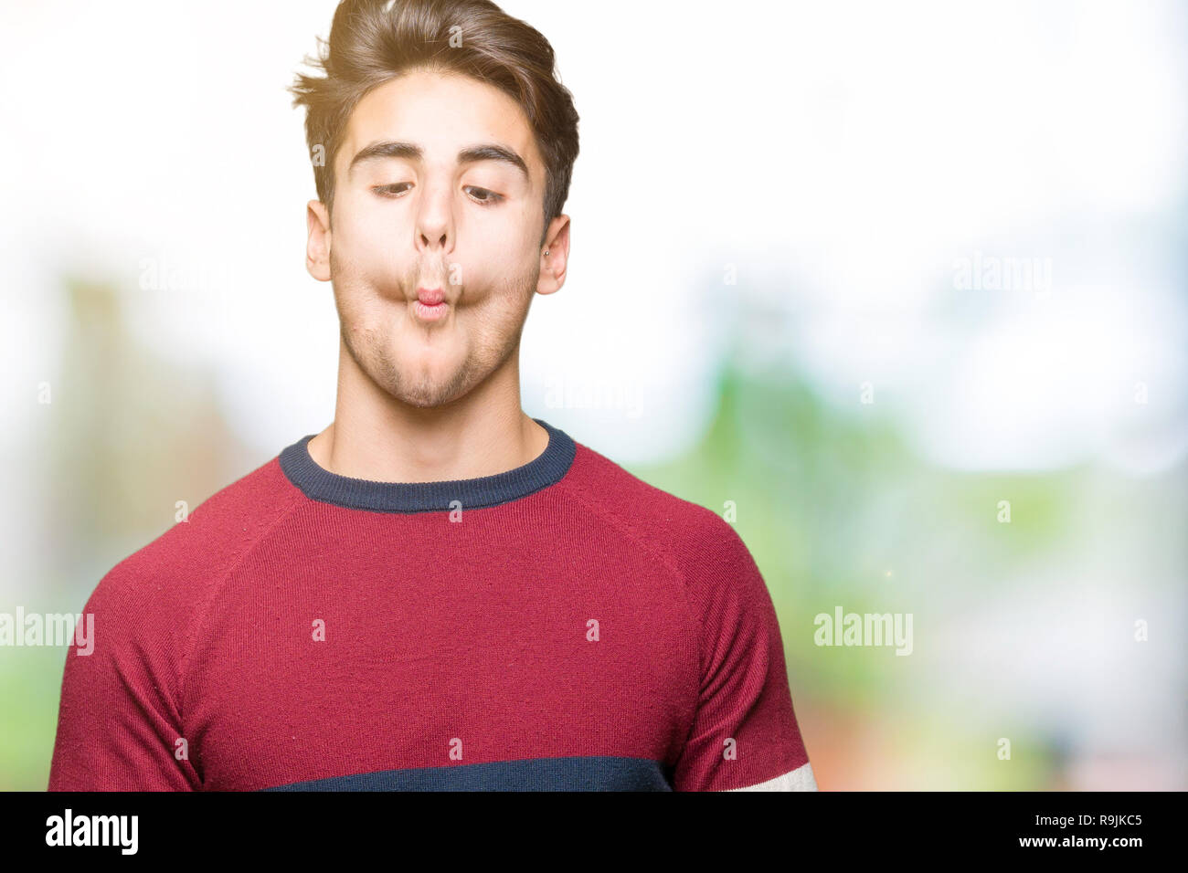 Young handsome man over isolated background making fish face with lips ...