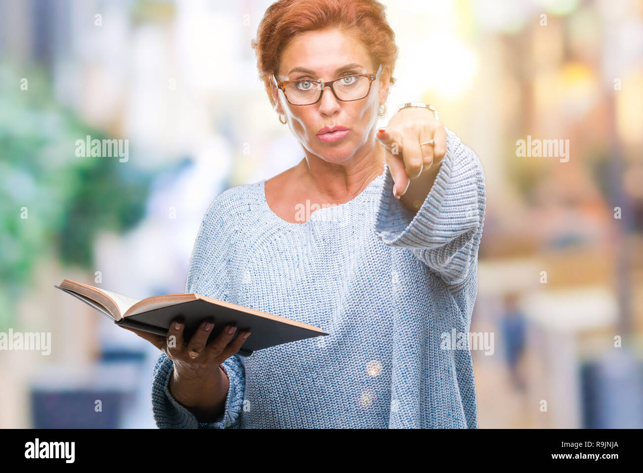 Senior caucasian woman reading a book over isolated background pointing ...