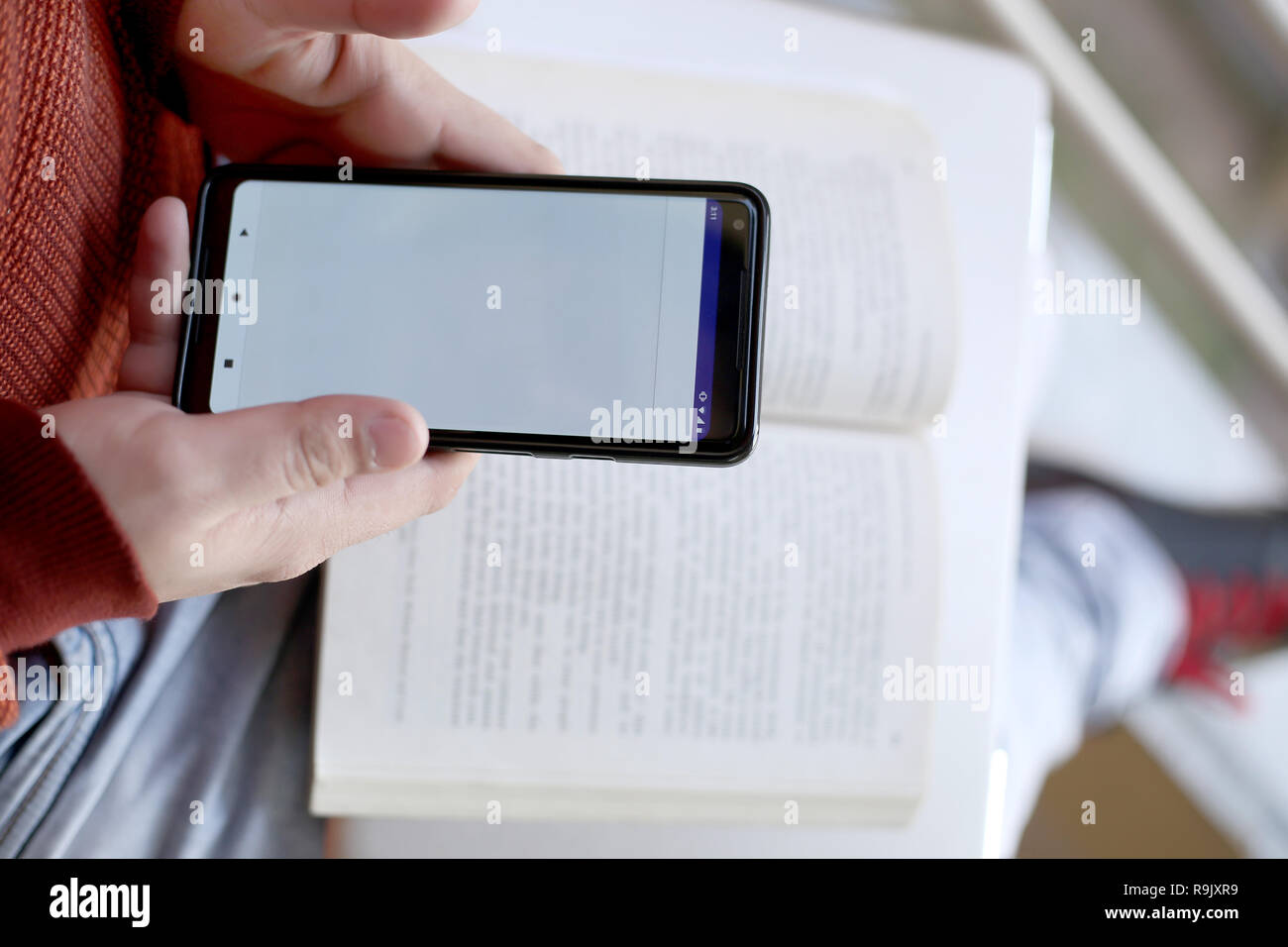 Boy is using phone with open book on the table Stock Photo - Alamy