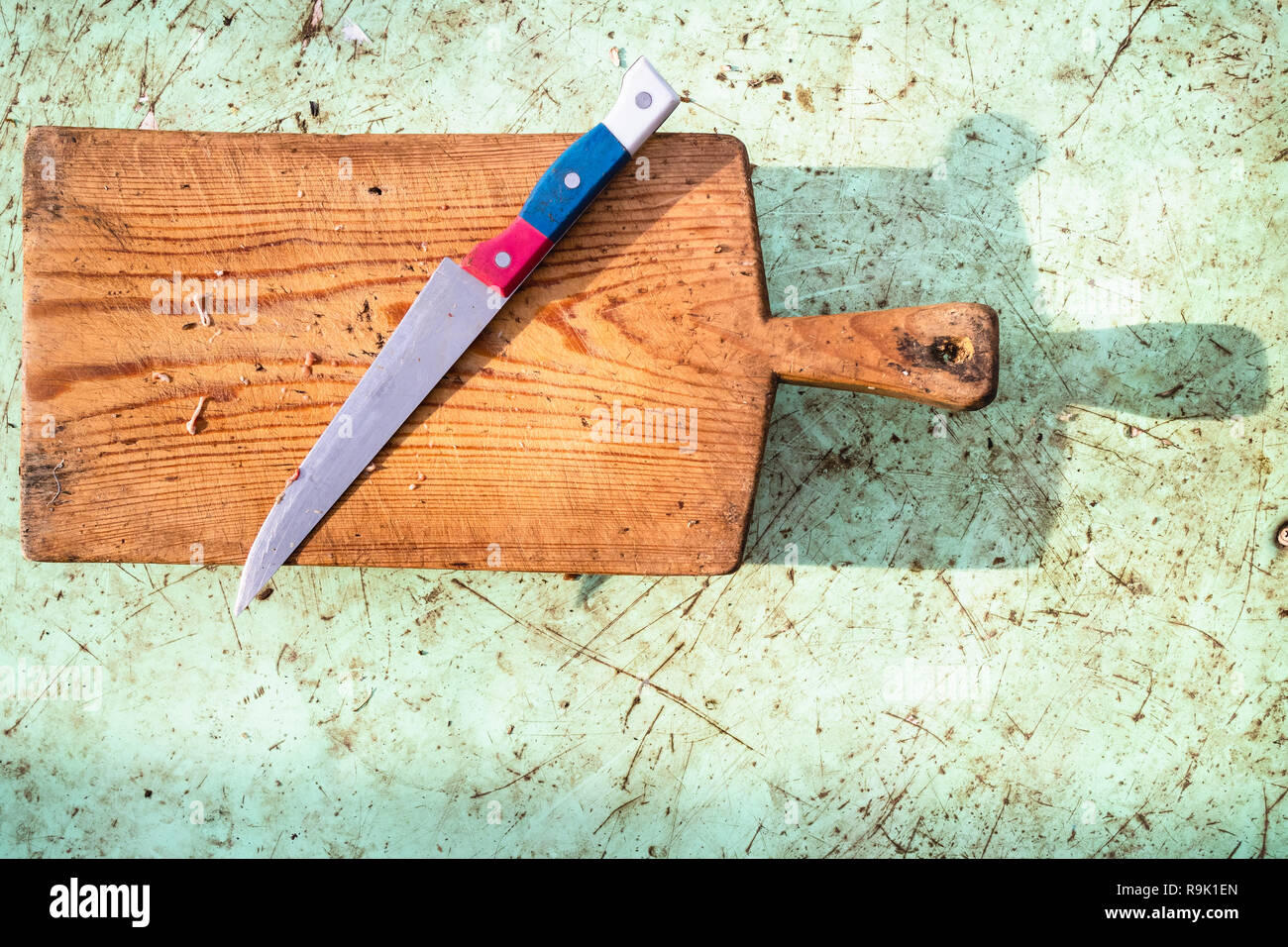 top view of steel knife with a red-blue-white handle on a dirty wooden ...
