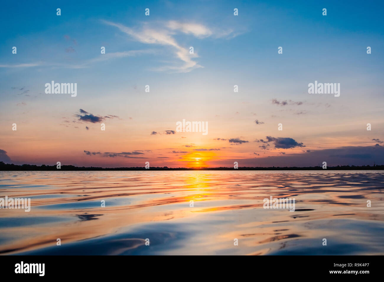 Sunset in the lake. beautiful sunset behind the clouds above the over ...