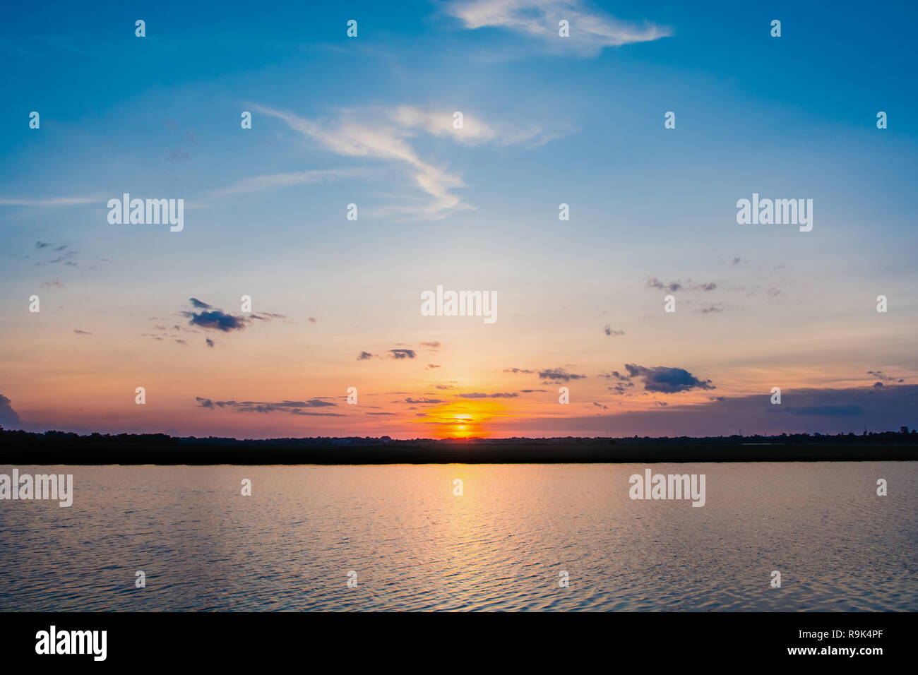 Sunset in the lake. beautiful sunset behind the clouds above the over lake landscape background ...