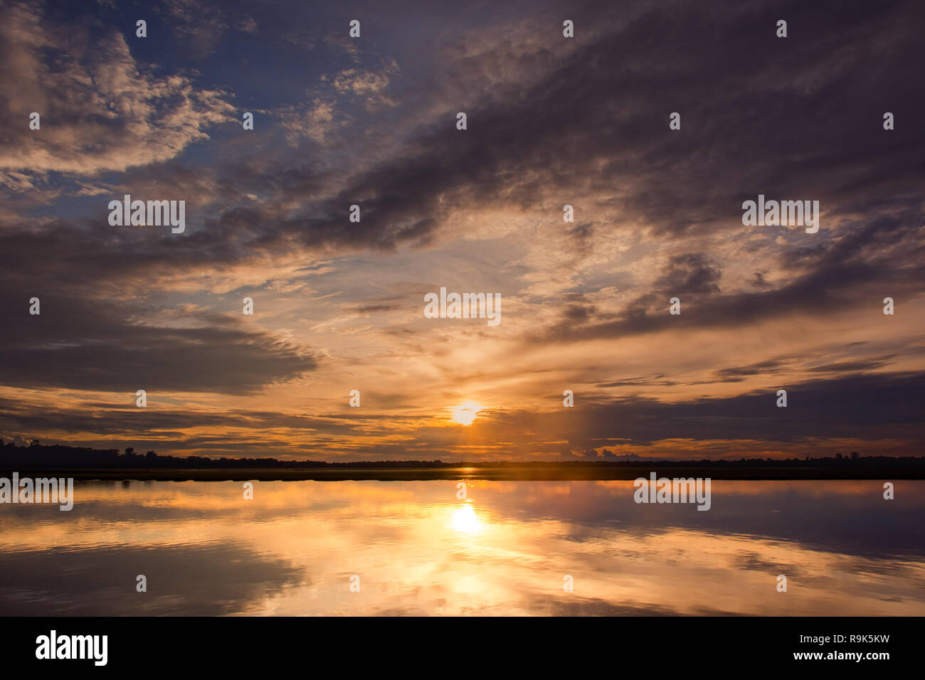 Sunset in the lake. beautiful sunset behind the clouds above the over lake landscape background ...