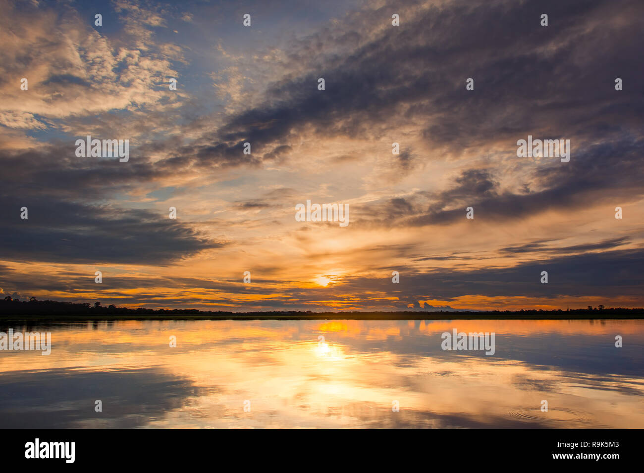 Sunset in the lake. beautiful sunset behind the clouds above the over lake landscape background ...
