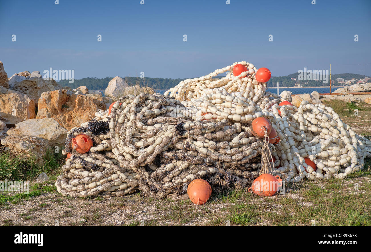 Fishing industry concept. Buoy from ship pilled up on the grassy rocky ...