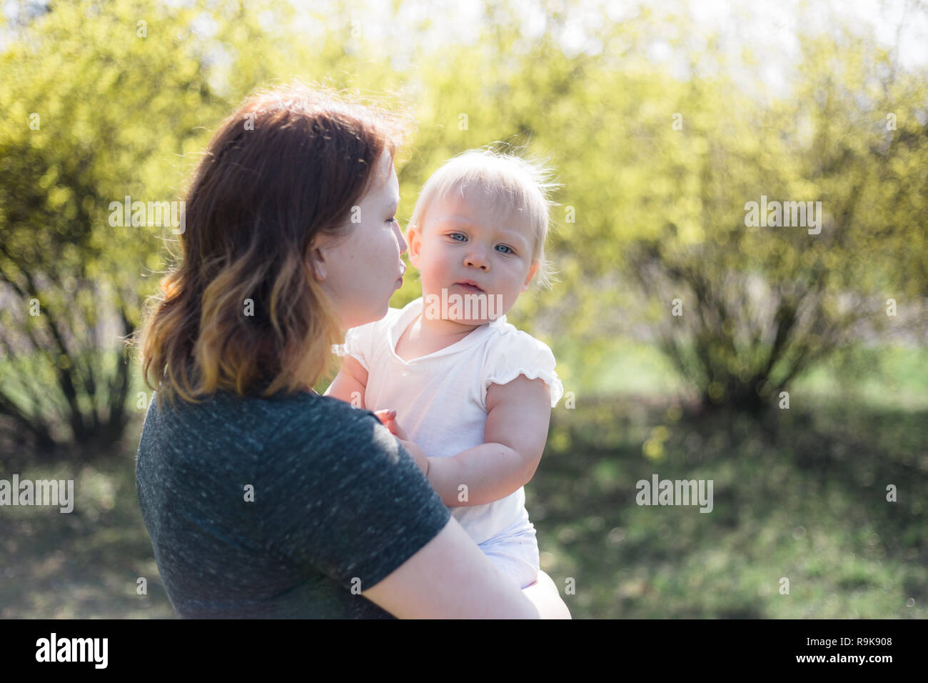 Mother smiling while wrapping her baby daughter in a sling for ...