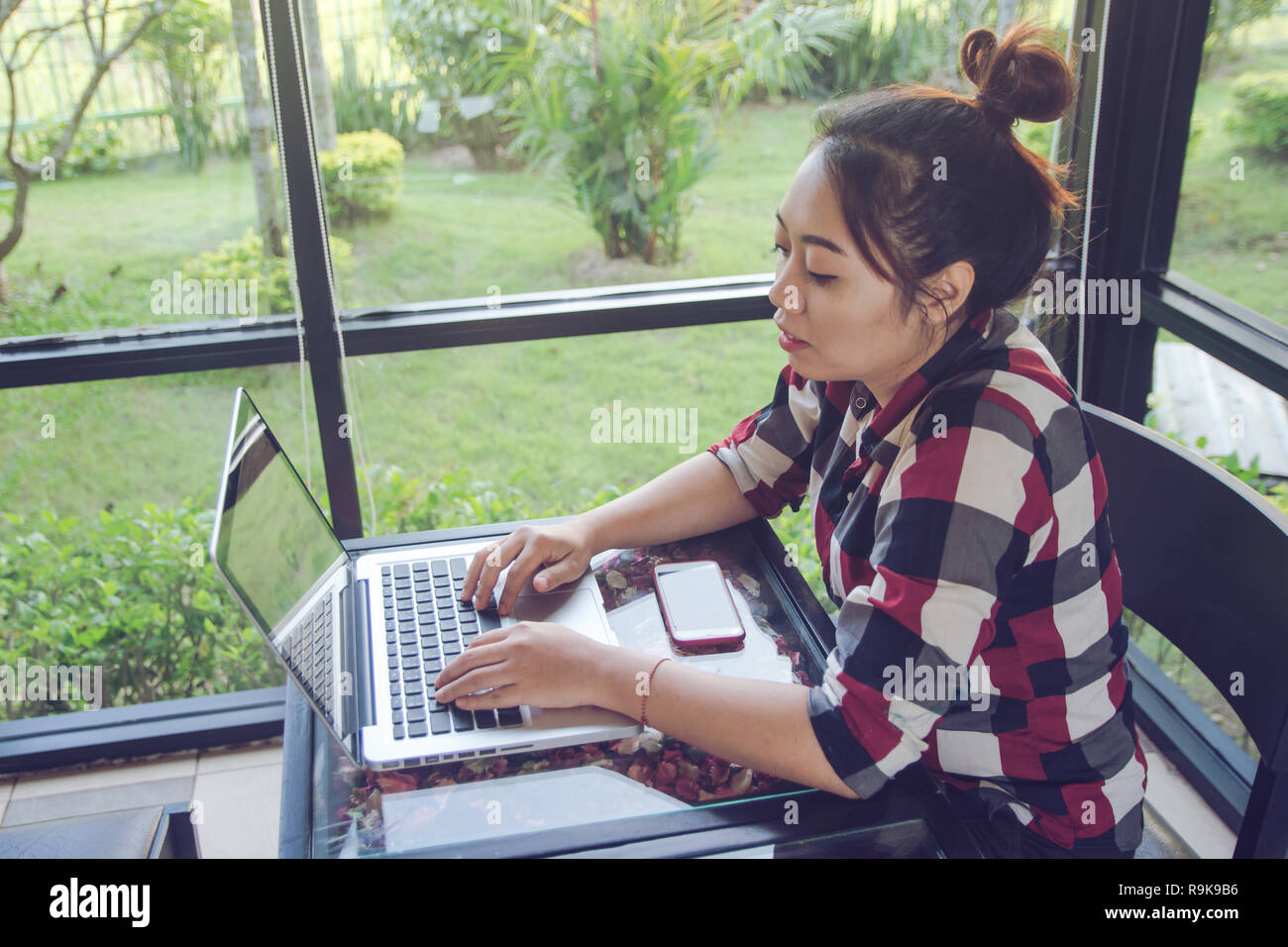 Young asia woman sitting alone and working on a laptop at coffee shop ...