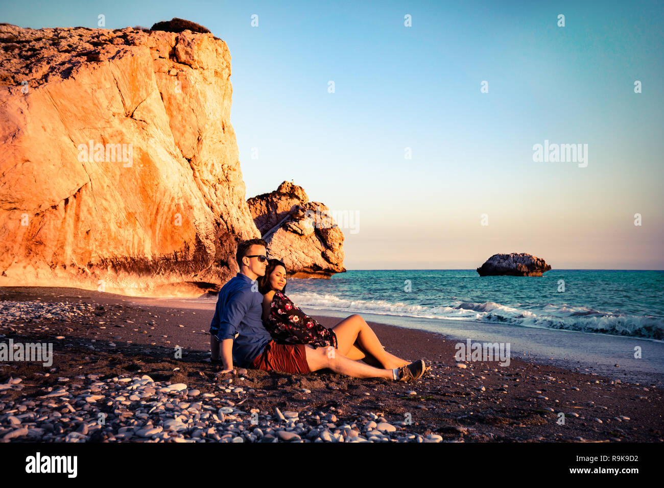 Young loving couple sitting together at the beach in front of the ...