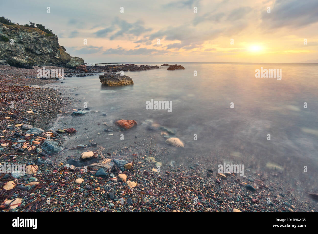 Stones and rocks in forefront with creamy surf ebbing and flowing on ...