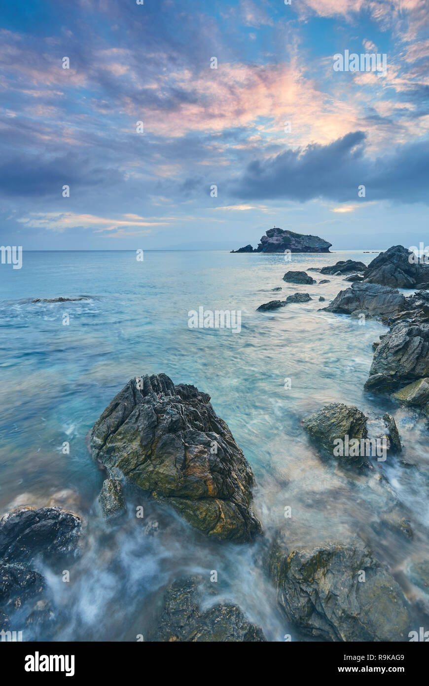 Stones and rocks in forefront with creamy surf ebbing and flowing on ...