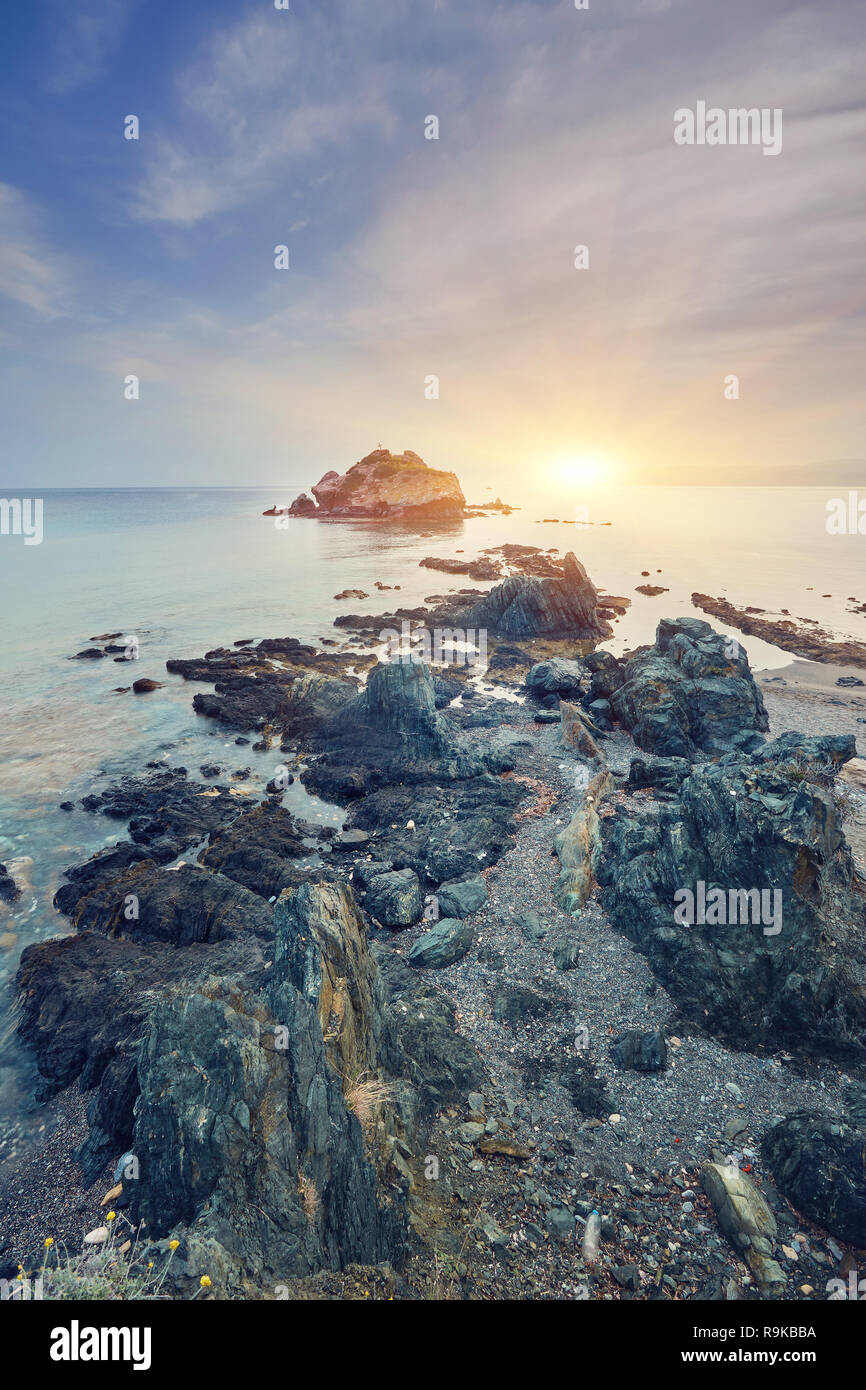 Stones and rocks in forefront with creamy surf ebbing and flowing on ...