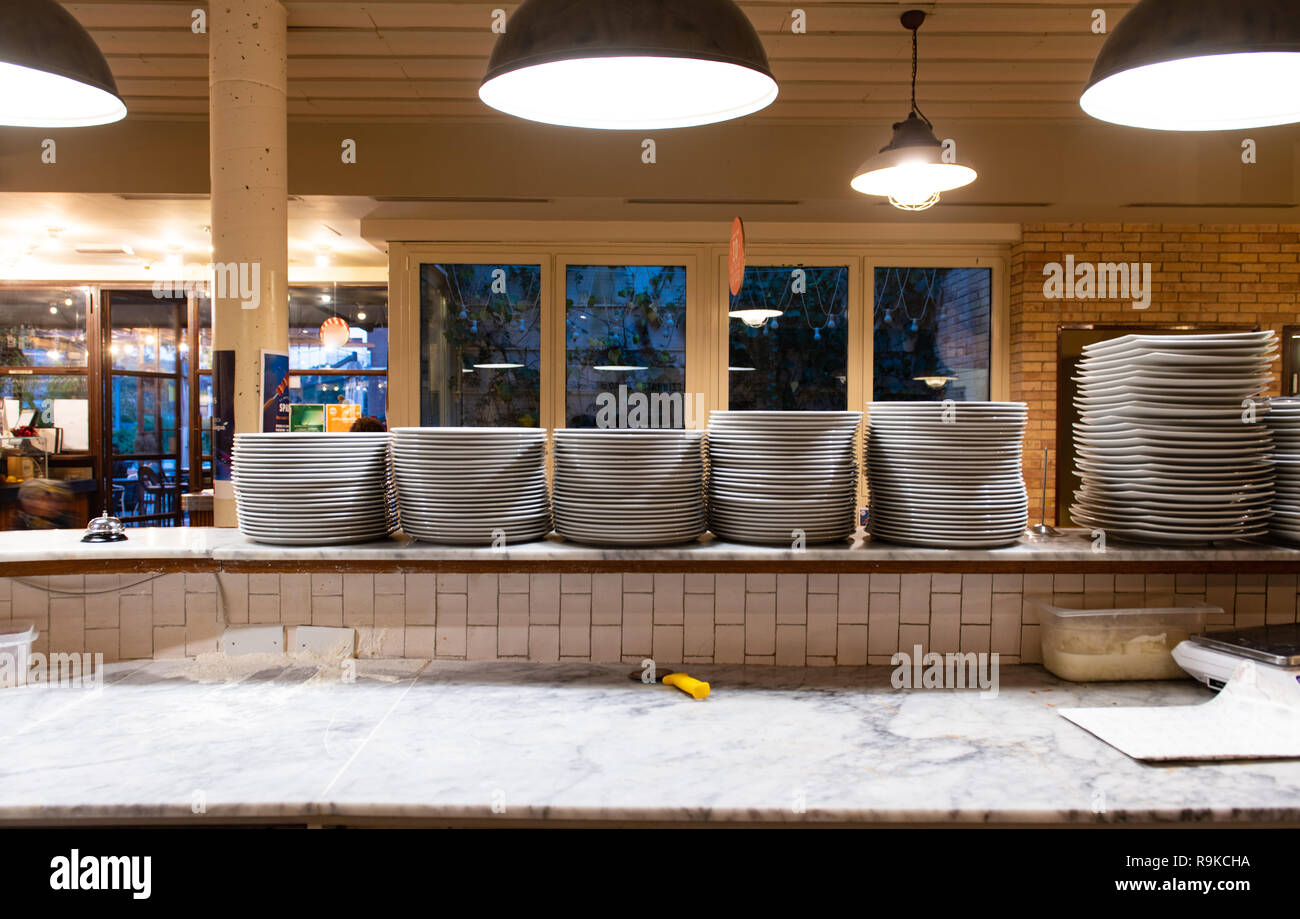 Wide shot of restaurant kitchen worktop, plie of plates, empty no ...
