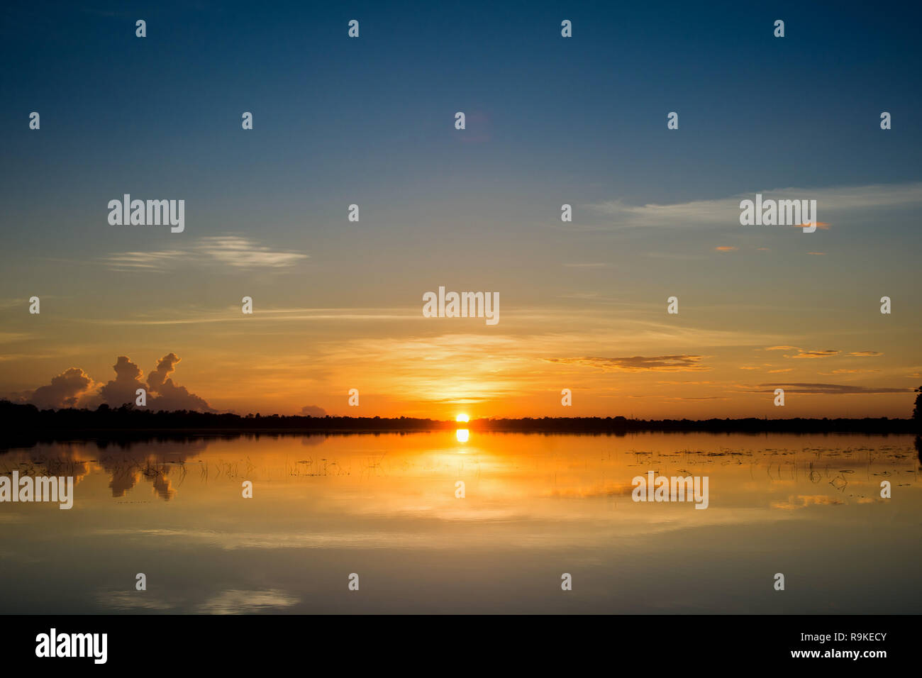 Sunset in the lake. beautiful sunset behind the clouds above the over lake landscape background ...