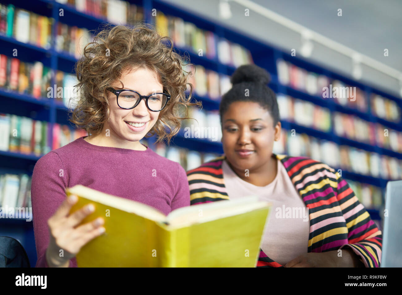 Positive students learning book together Stock Photo - Alamy