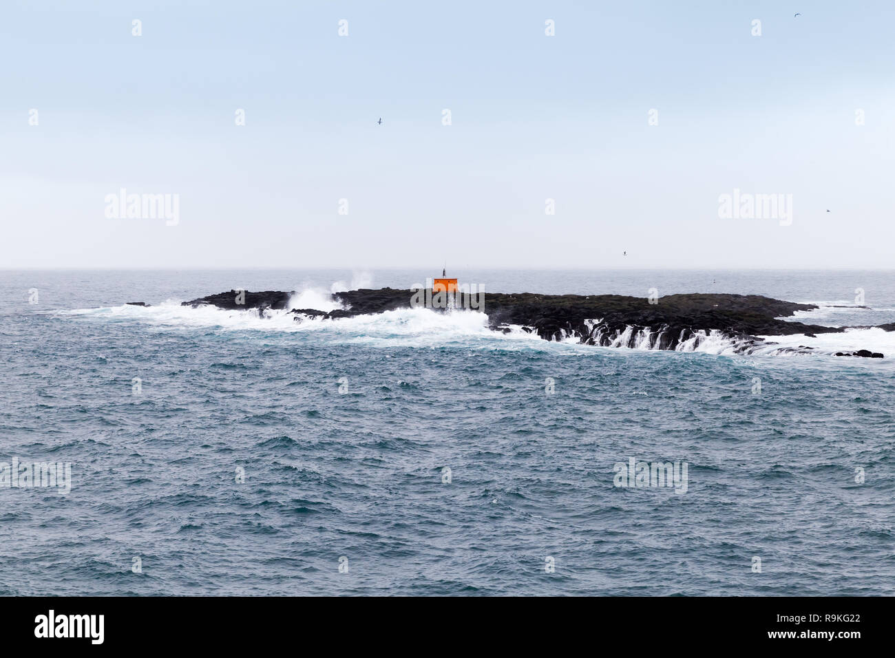 Red navigation mark on small rocky island in Atlantic ocean, Iceland ...
