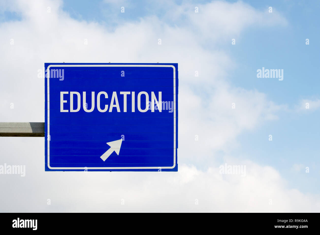 Blue road sign displaying Education word on blue sky and white clouds ...