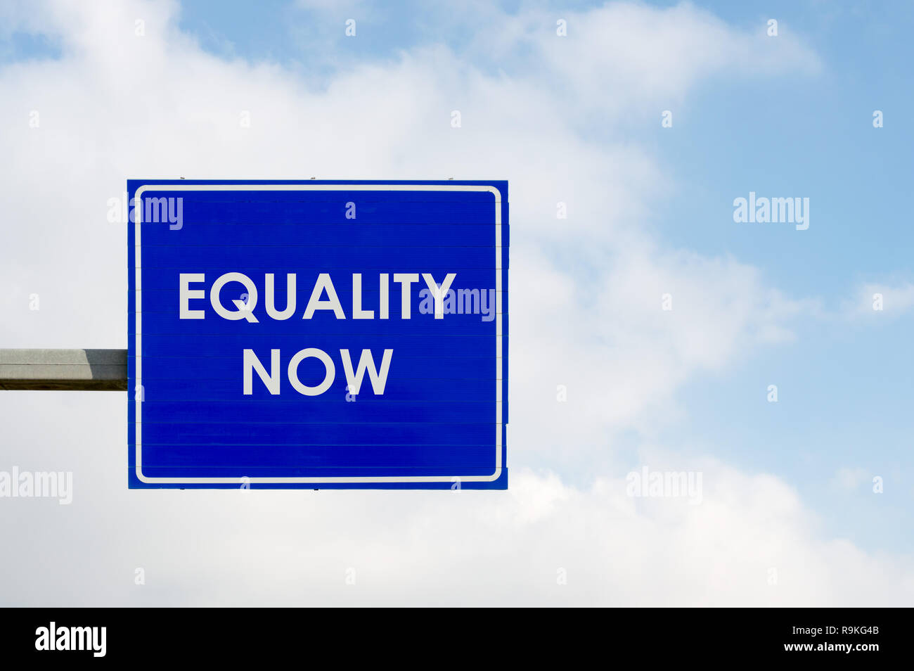 Blue road sign displaying Equality Now words on blue sky and white ...
