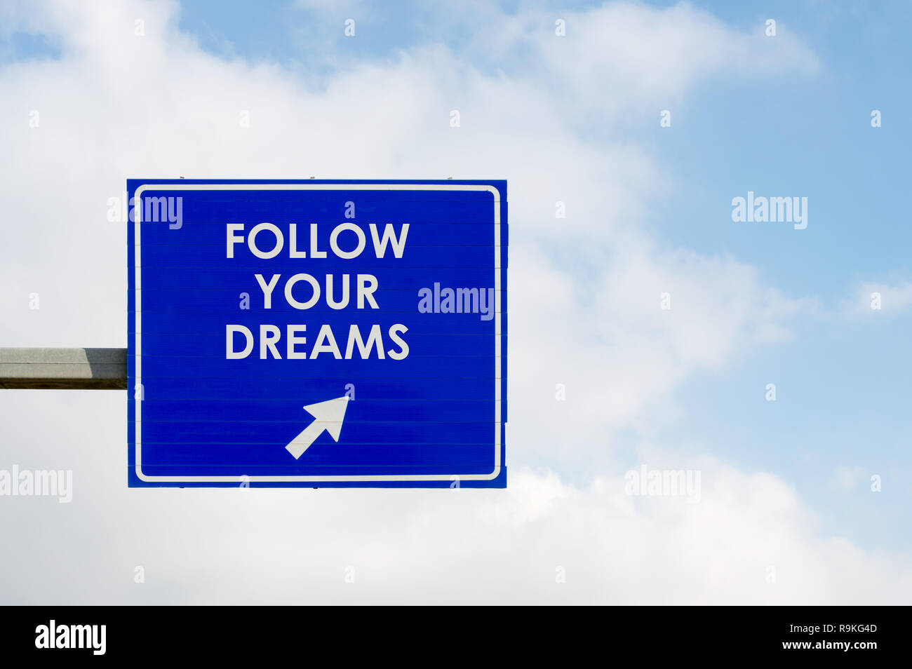 Blue road sign displaying Follow Your Dreams words on blue sky and ...