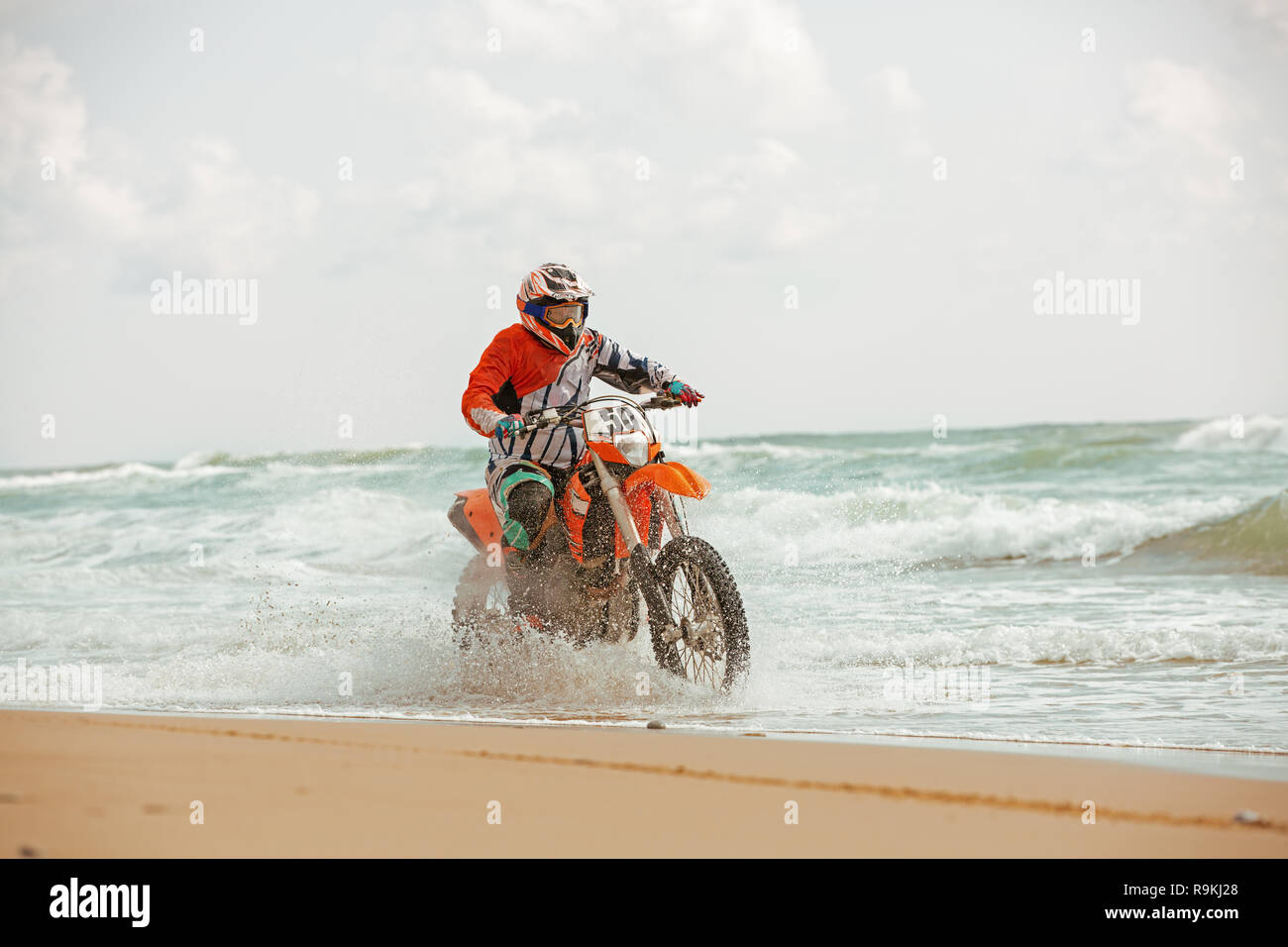 Motorcyclist in a protective suit rides a motorcycle on the sea ...