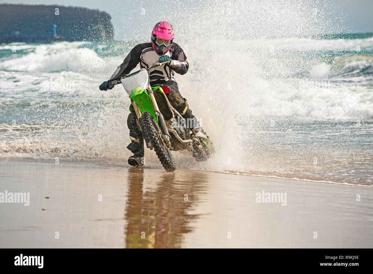 Motorcyclist in a protective suit rides a motorcycle on the sea ...
