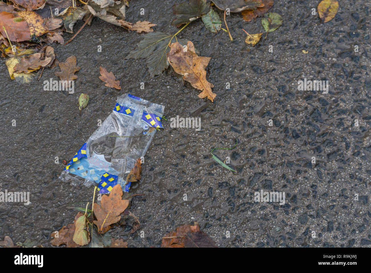Plastic takeaway food wrapper discarded on rural country road. Metaphor ...